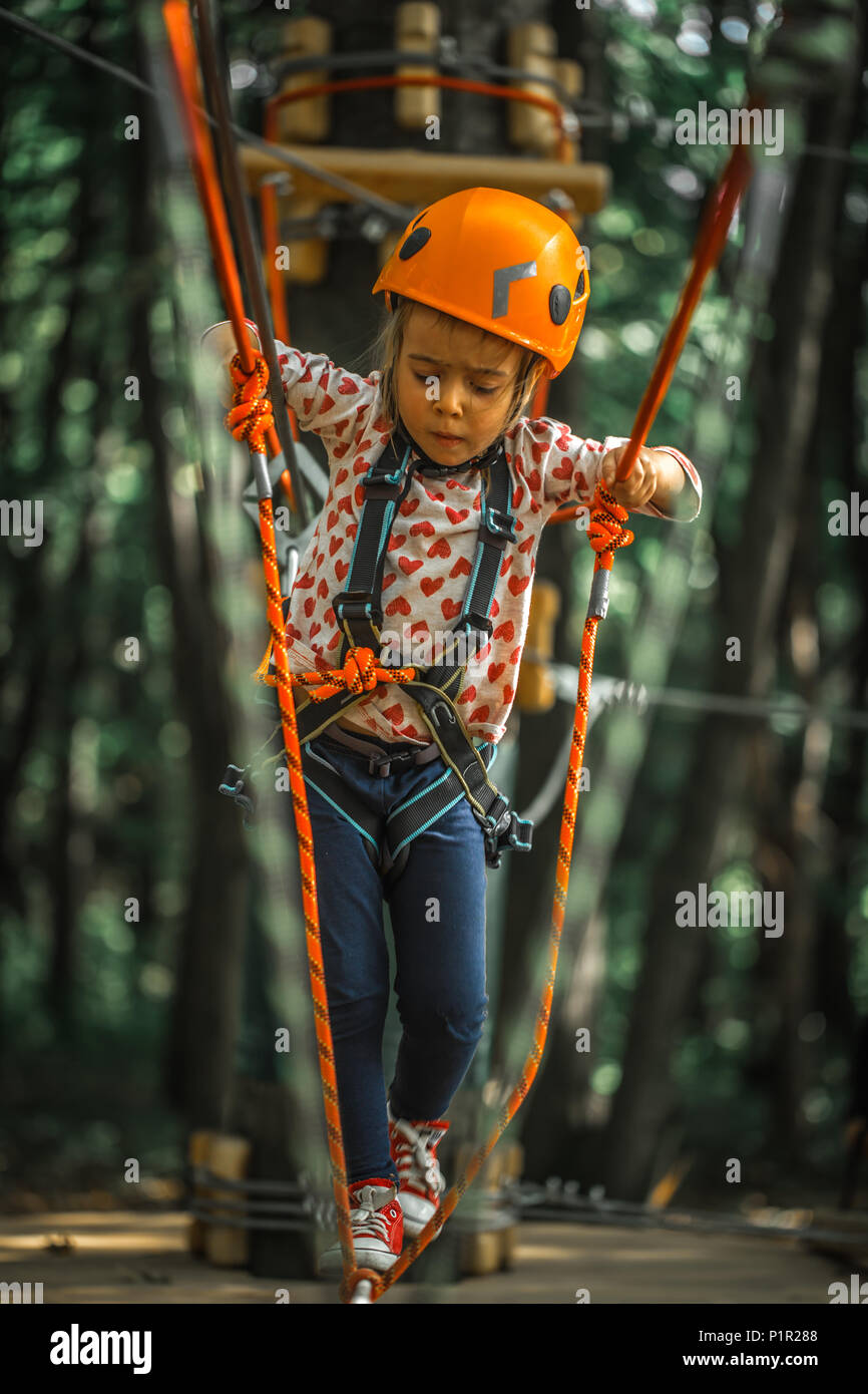 sports happy kid climbs through the ropes, the beautiful girl in the ...
