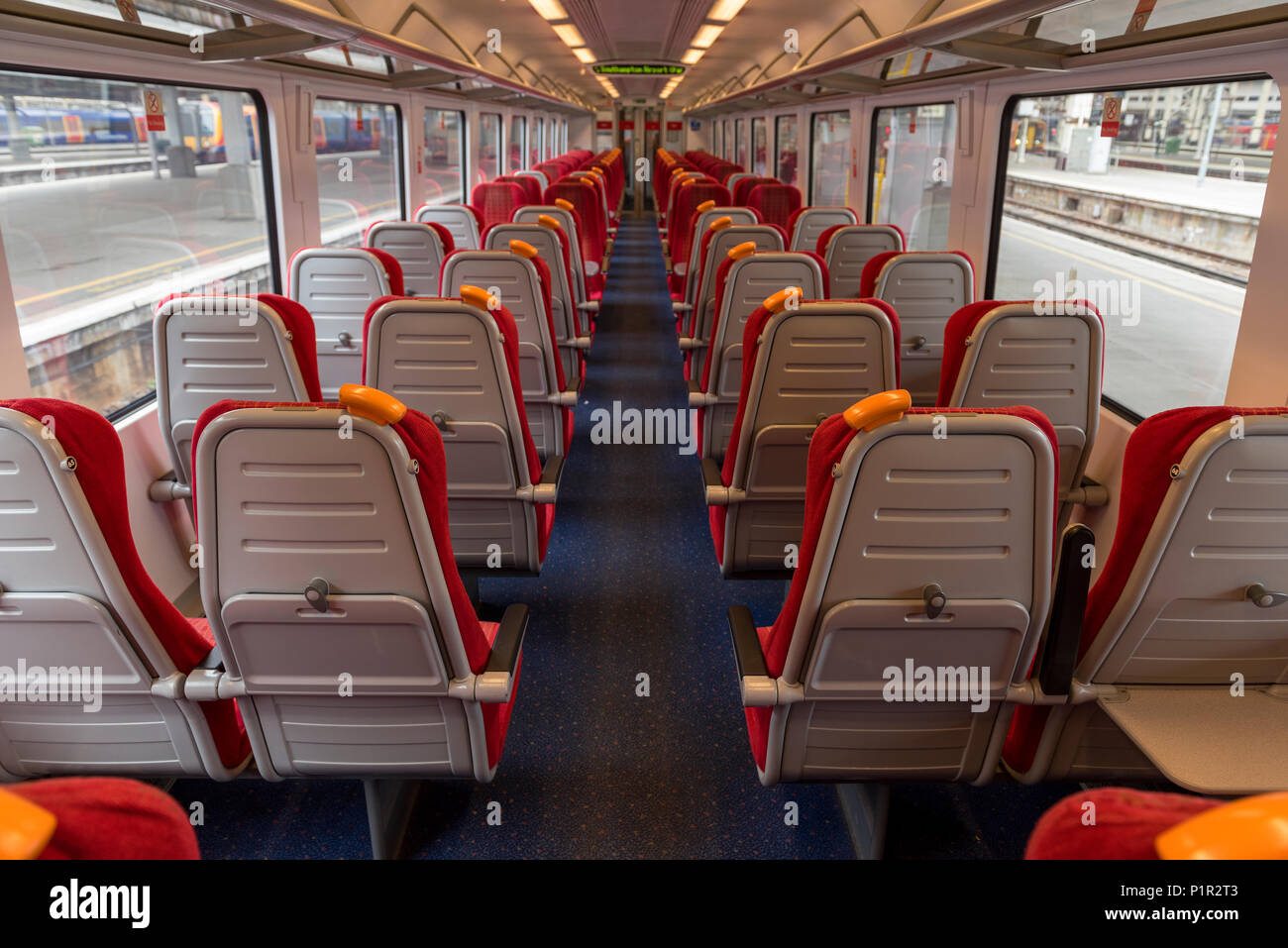the inside of a modern railway carriage with red seats and windows at ...