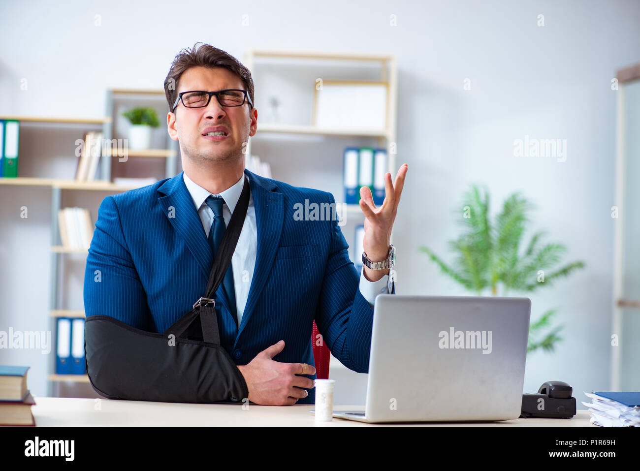 Businessman with broken arm working in office Stock Photo - Alamy