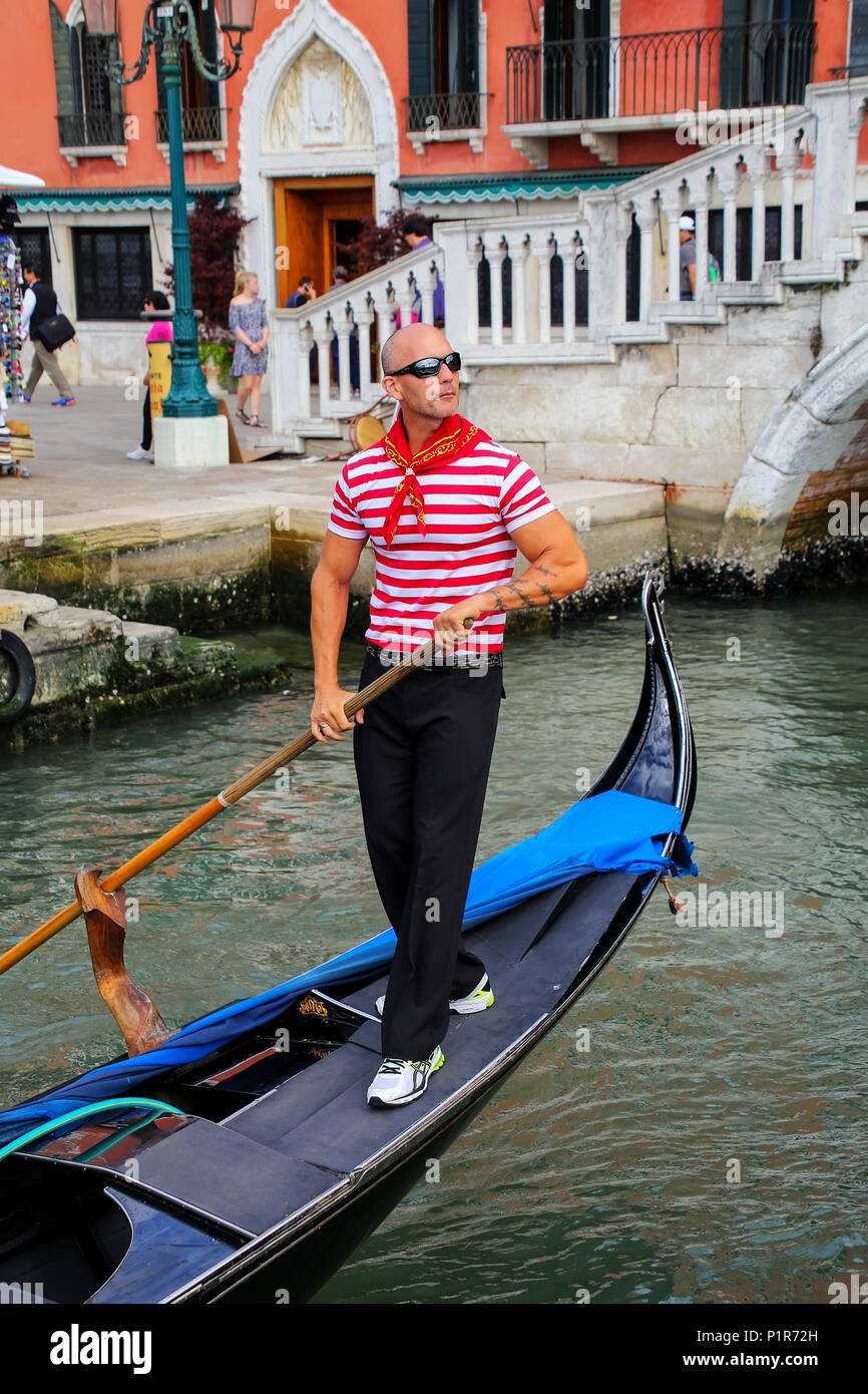 Man rowing gondola in Venice, Italy. Venice is situated across a group ...