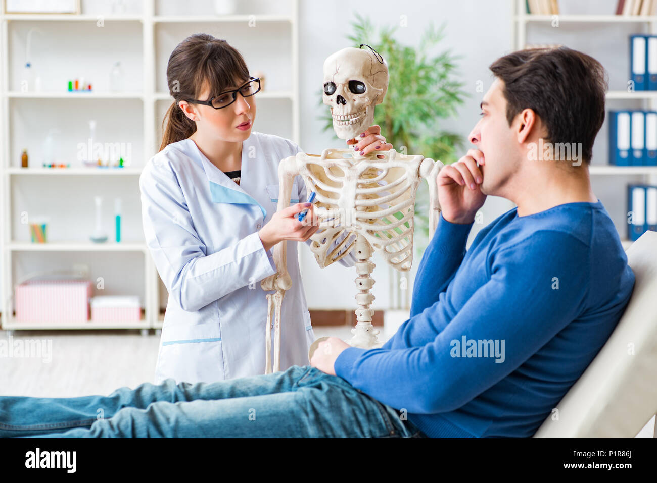 Doctor showing type of injury on skeleton to patient Stock Photo - Alamy