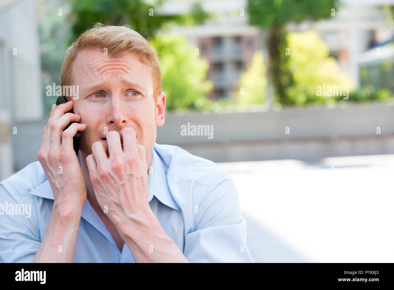 Closeup portrait, worried young man in blue shirt talking on phone to ...