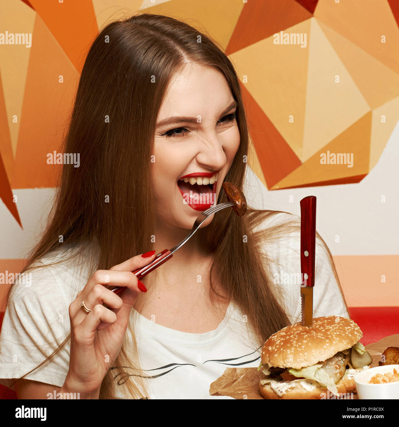 Happy attractive woman holding fork and round wooden plate with ...