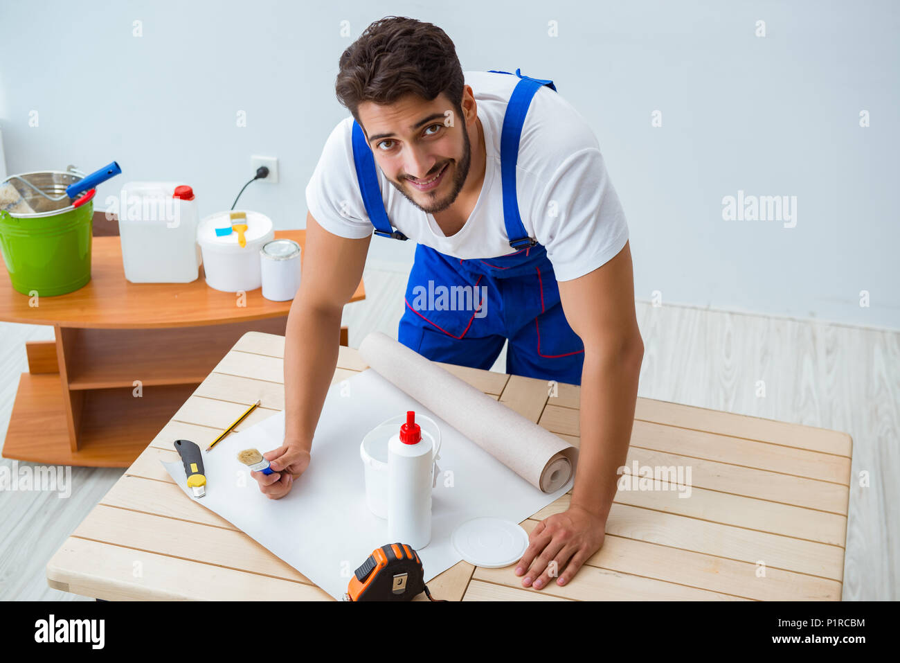 Worker working on wallpaper during refurbishment Stock Photo - Alamy