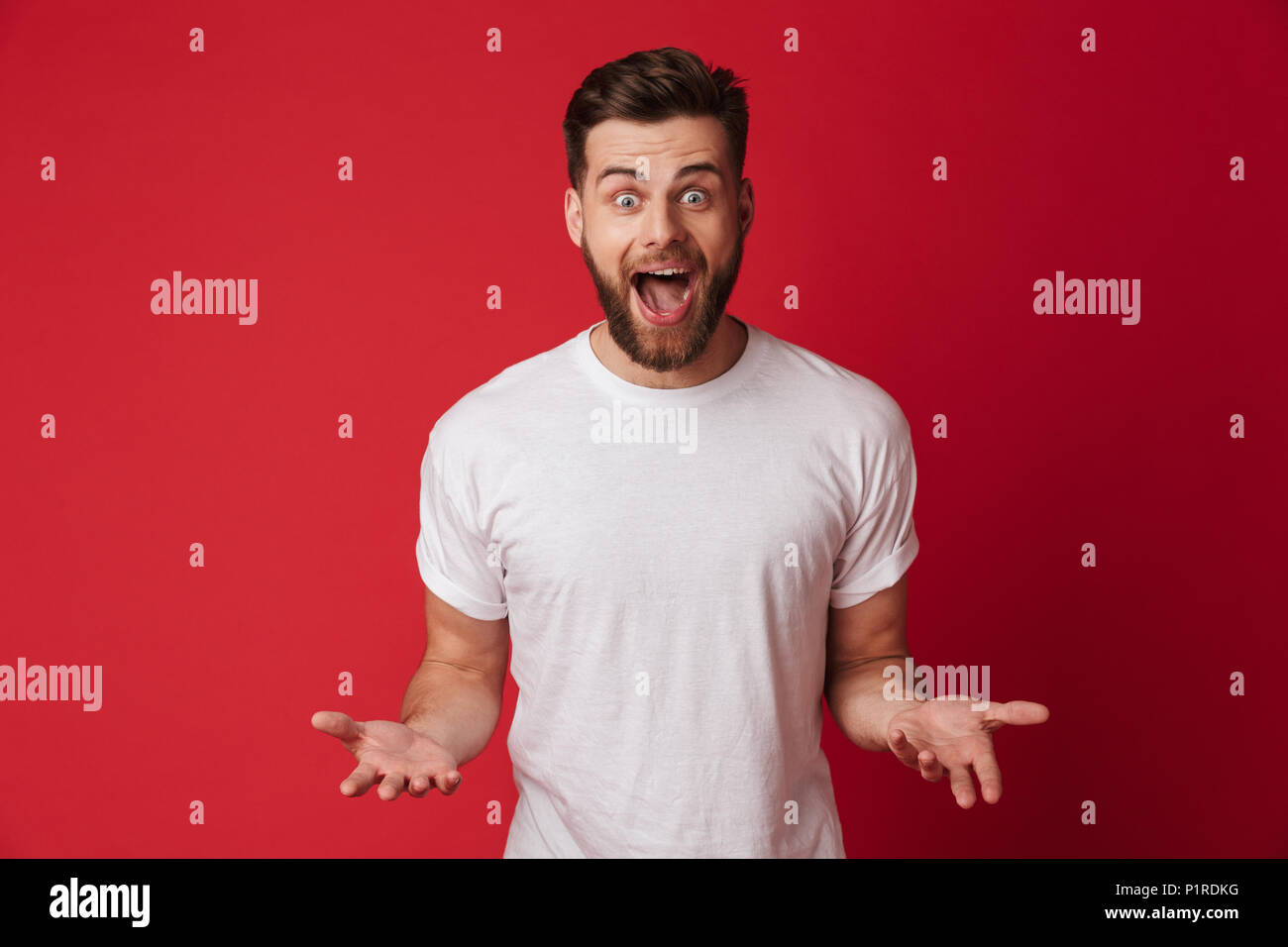 Picture of shocked young handsome man standing isolated over red wall ...