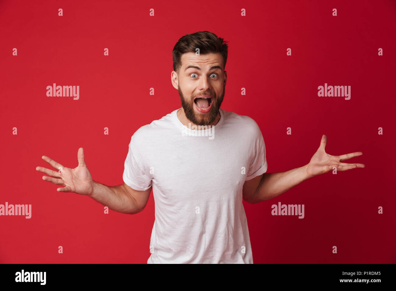 Picture of shocked young handsome man standing isolated over red wall ...