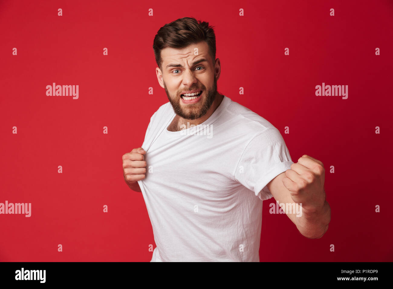 Image of angry emotional young man standing isolated over red wall ...