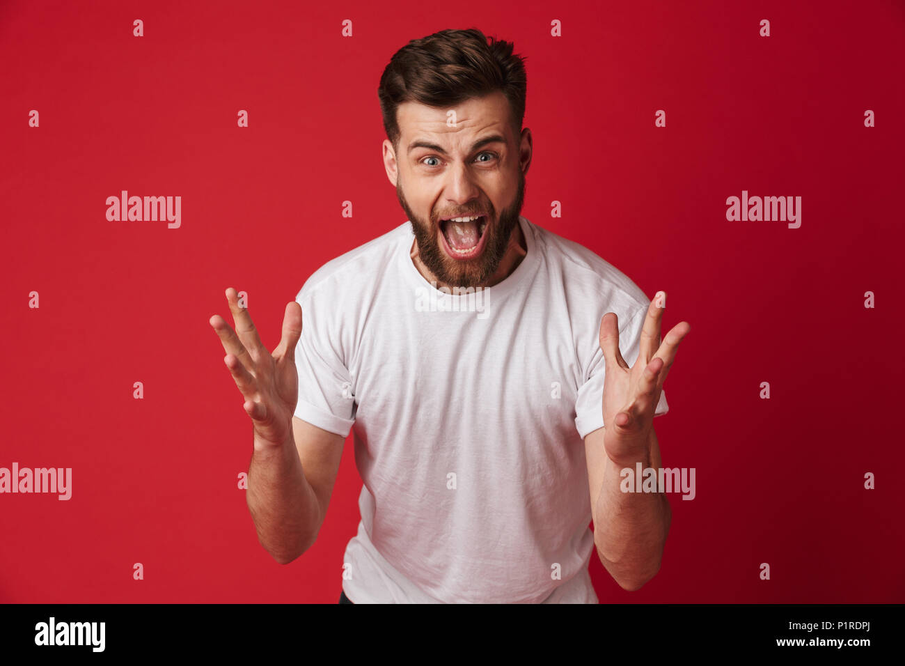 Image of angry emotional young man standing isolated over red wall ...