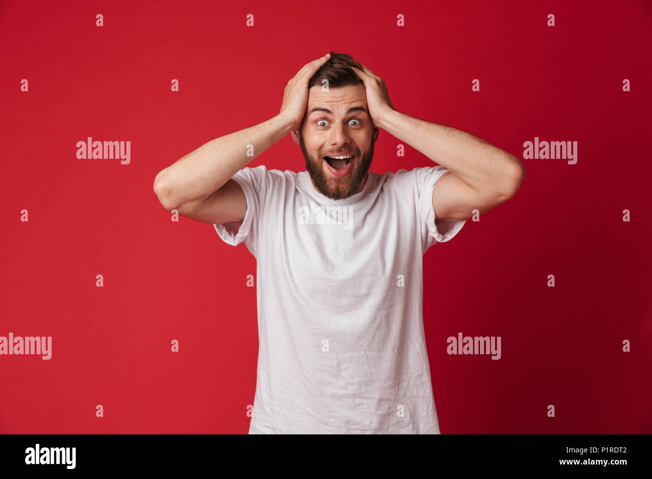 Picture of shocked young handsome man standing isolated over red wall ...