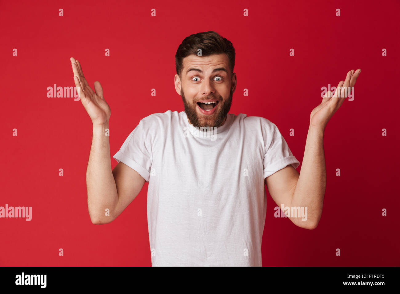 Picture of shocked young handsome man standing isolated over red wall ...