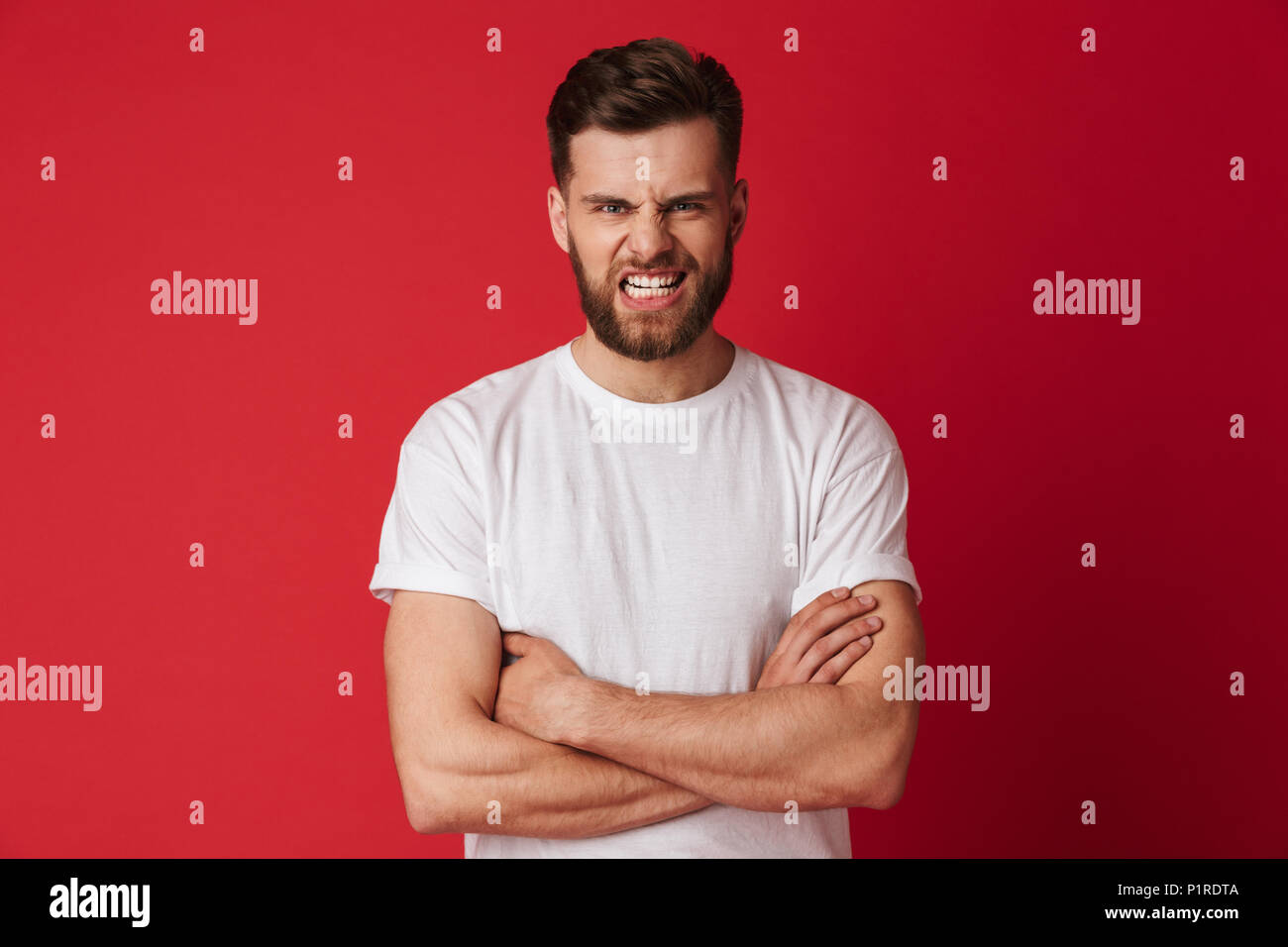 Image of angry emotional young man standing isolated over red wall ...