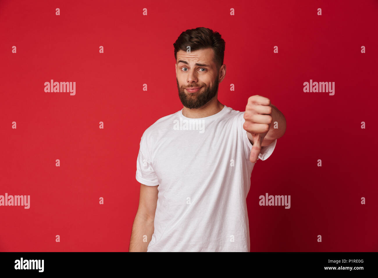 Image of sad young man showing thumbs down standing isolated over red ...