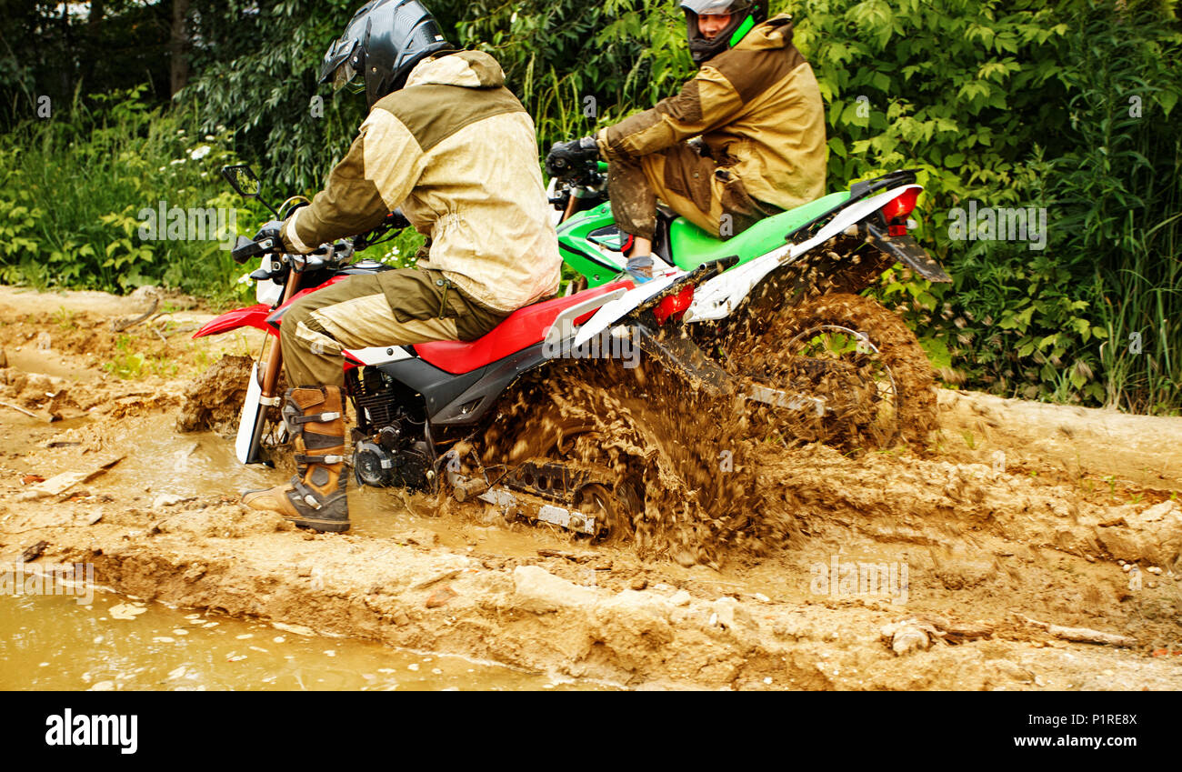 Two mens on a motorcycle rides through the mud Stock Photo - Alamy