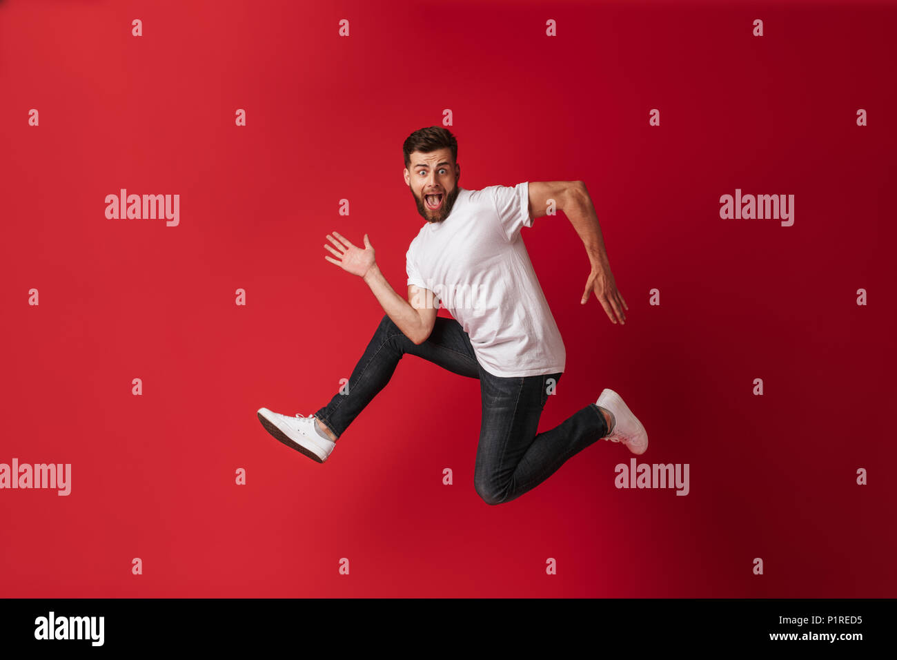 Photo of handsome excited young man running isolated over red wall ...