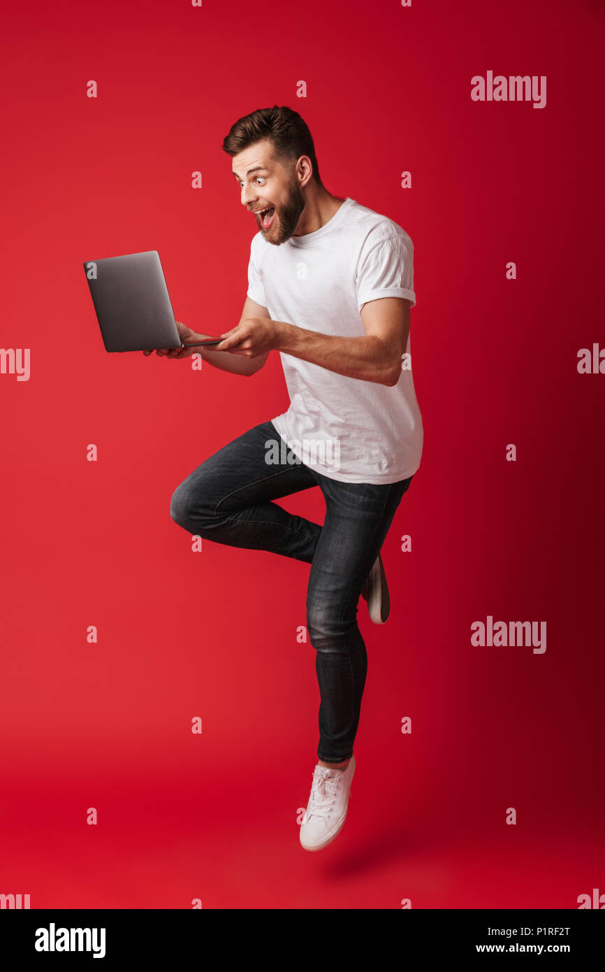 Image of surprised young man jumping isolated over red wall background ...