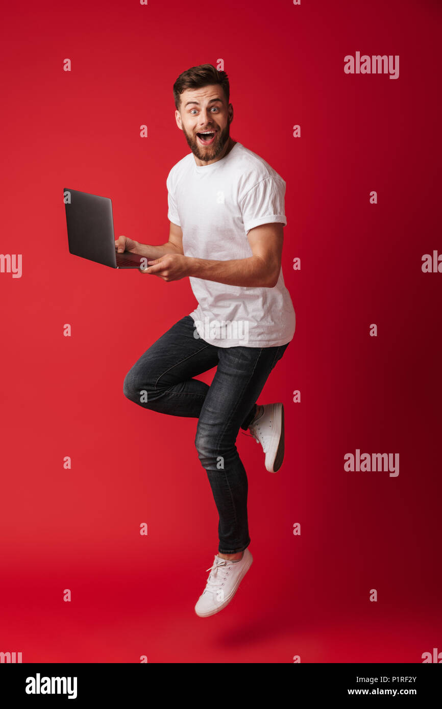 Image of surprised young man jumping isolated over red wall background ...