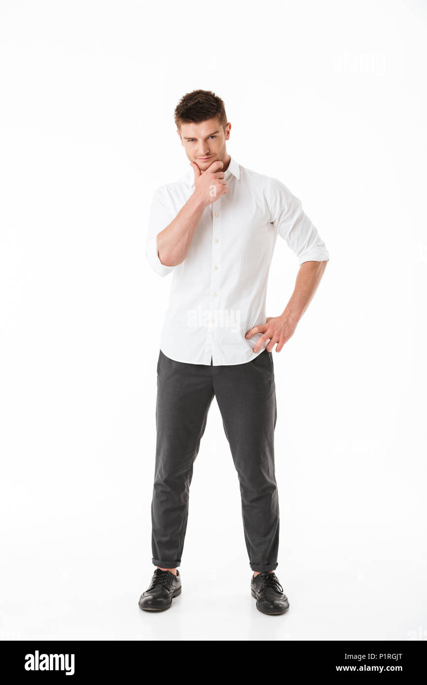 Full length portrait of a pensive young man looking at camera isolated ...