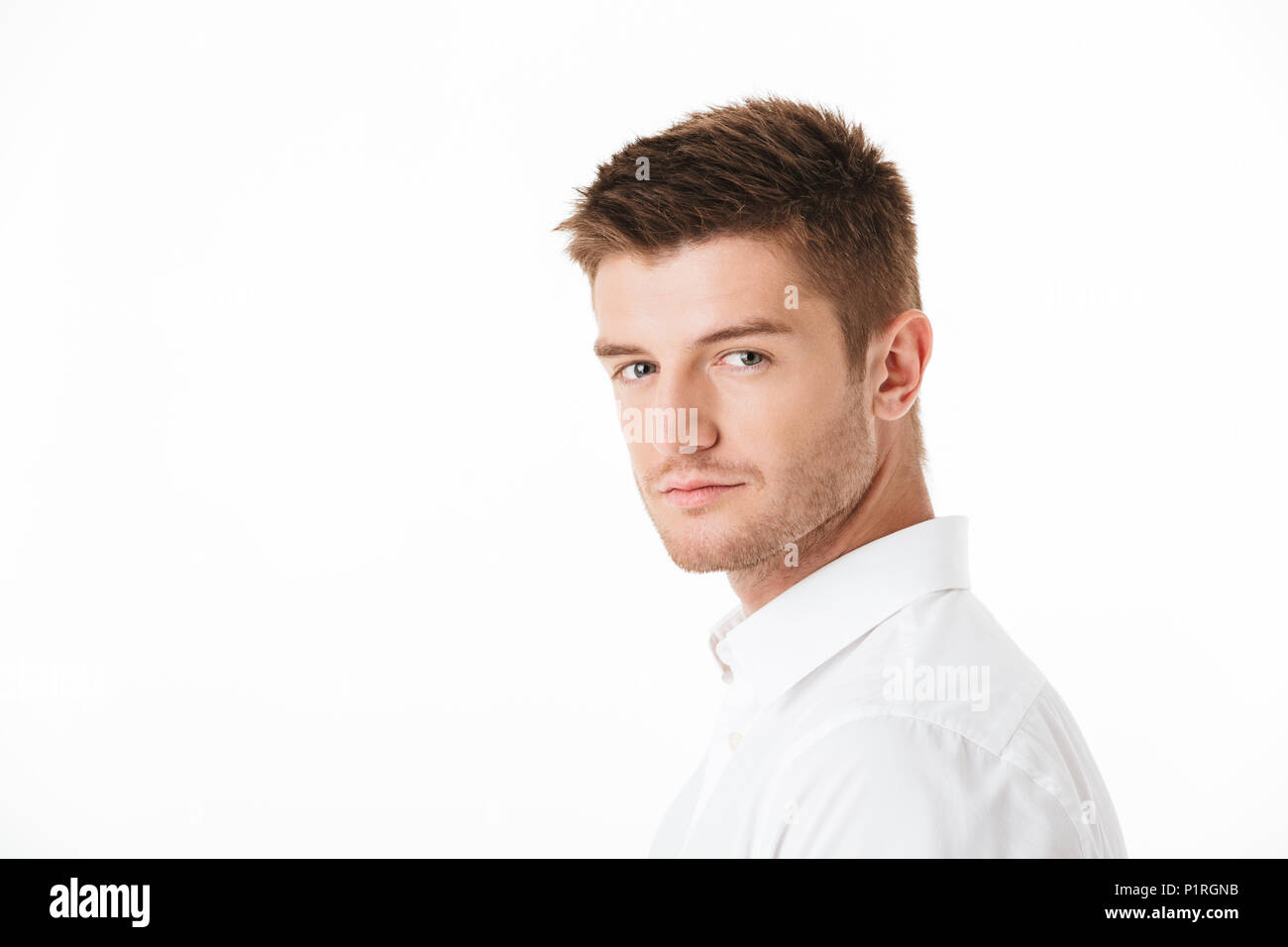 Portrait of a charming young man looking at camera isolated over white ...