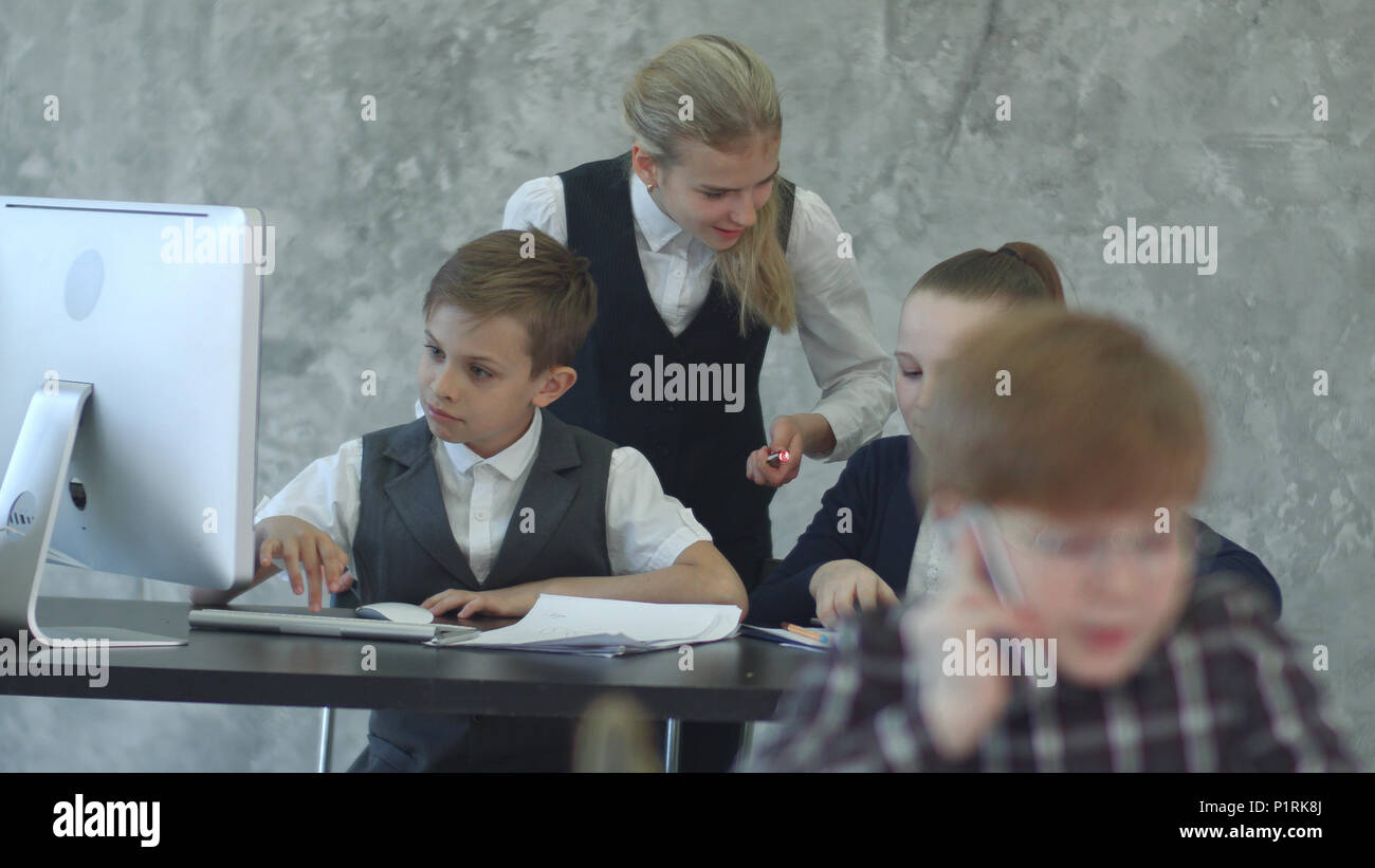 Three little children in business suits sitting at table with laptop ...