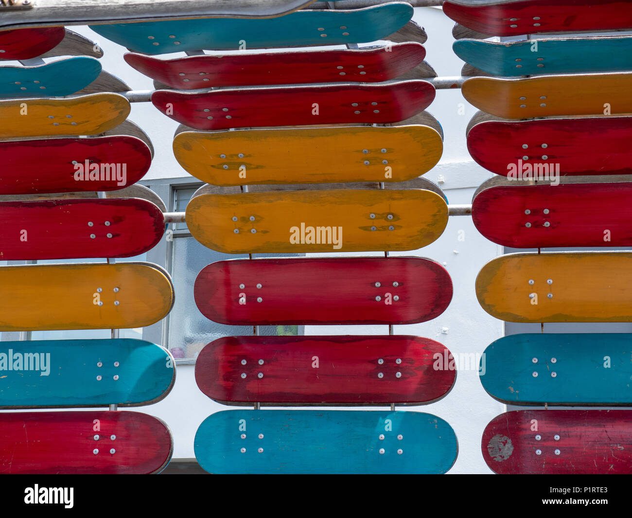 Some red, orange, and teal skateboard decks mounted on an installation ...