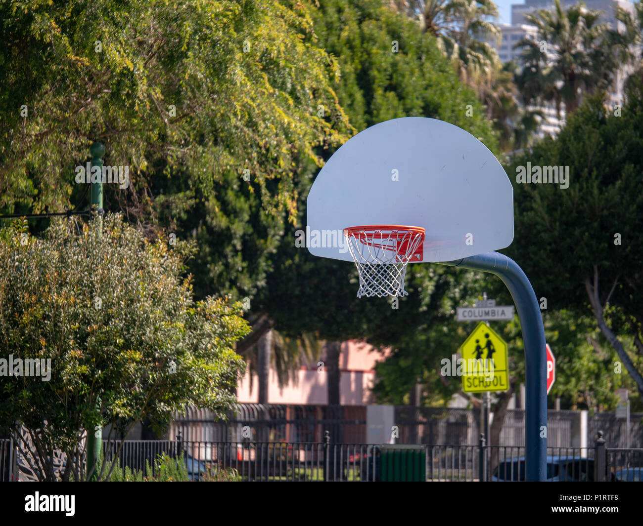 An outdoor basketball hoop sitting on a court in a school zone ...