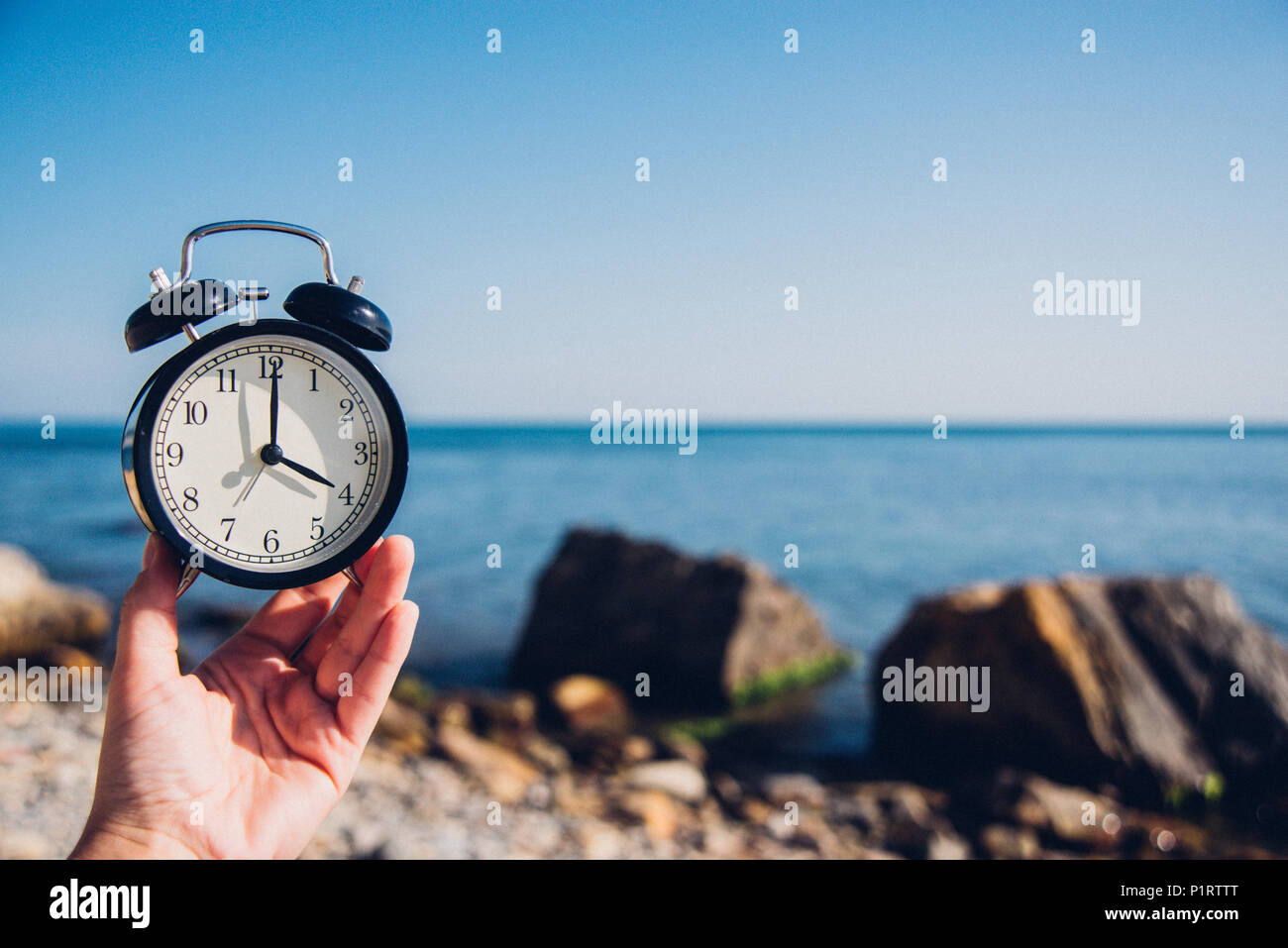 Hand hold watch on beach background.Alarm clock on sea and sand ...
