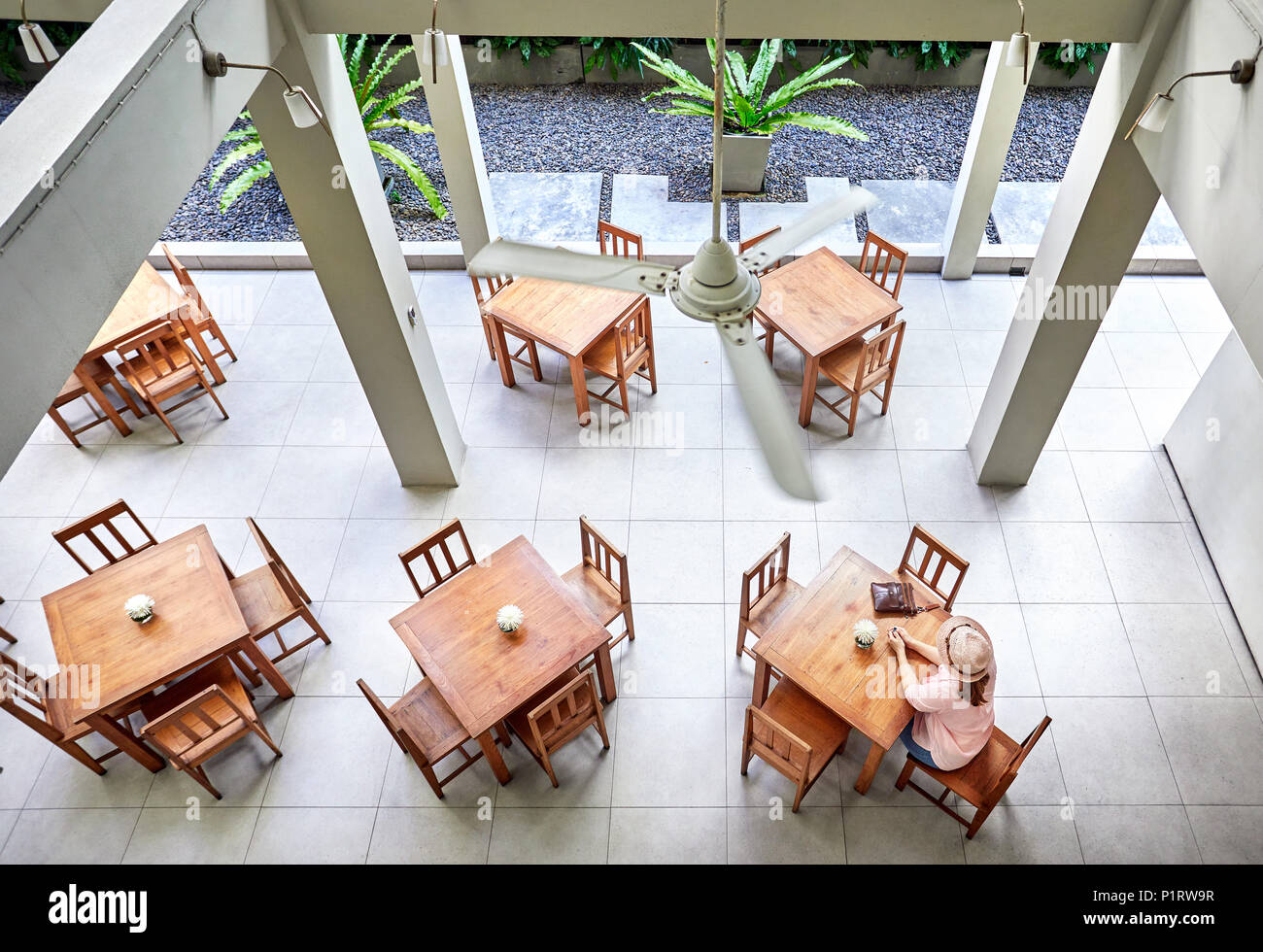 Woman in pink shirt and hat sitting at the table in hotel restaurant ...