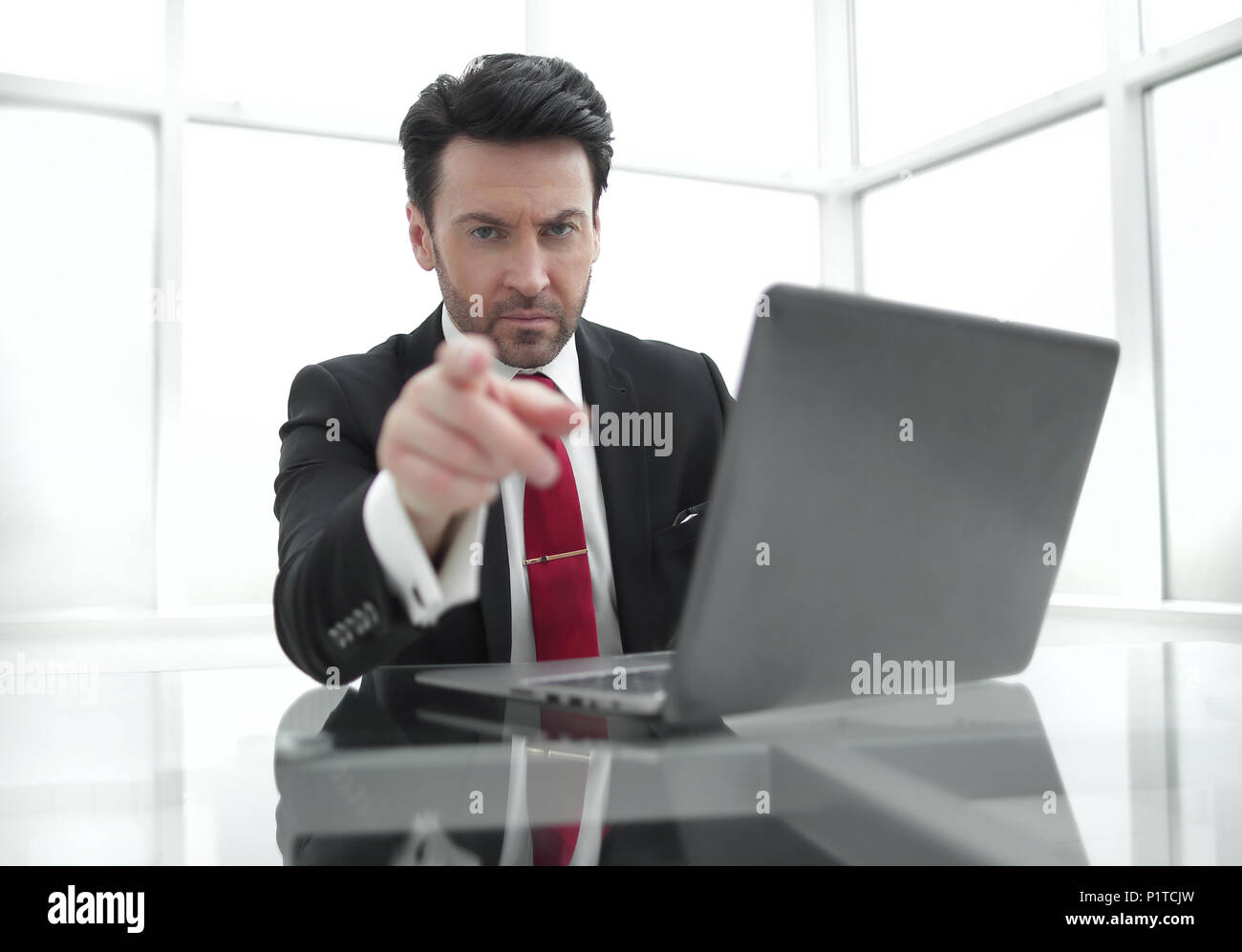 serious Businessman pointing the finger at you,sitting at his Desk ...