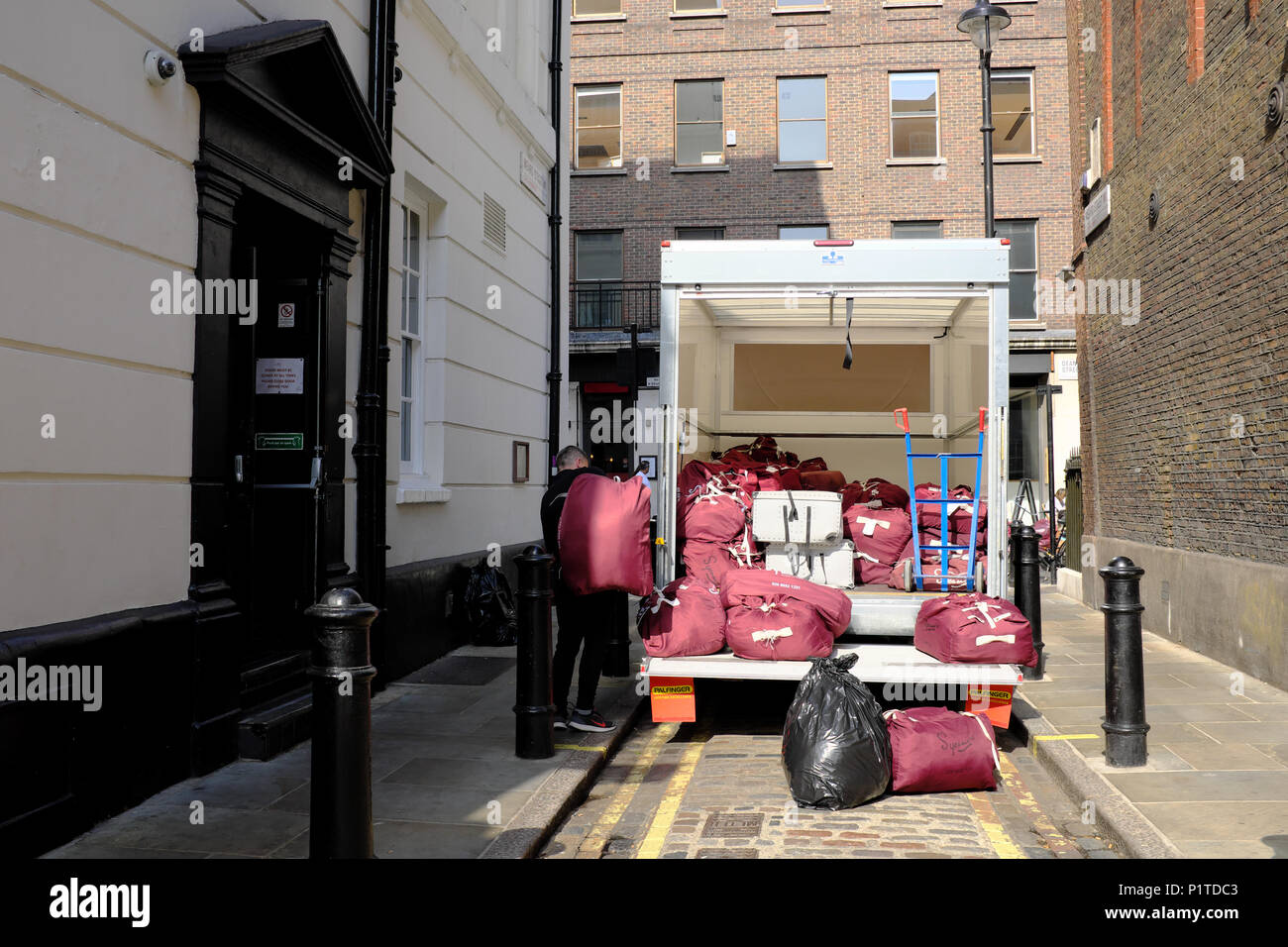 Man loading Laundry sacks into truck in alley, Soho, London, England ...