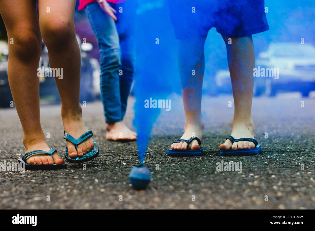 Blue smoke bomb in the street smoking with children in the background ...