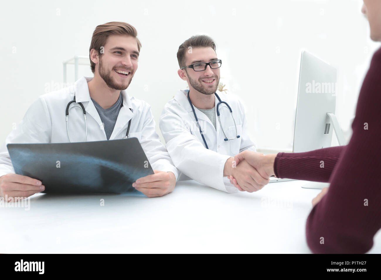 Smiling doctor at the clinic giving an handshake to his patient Stock ...