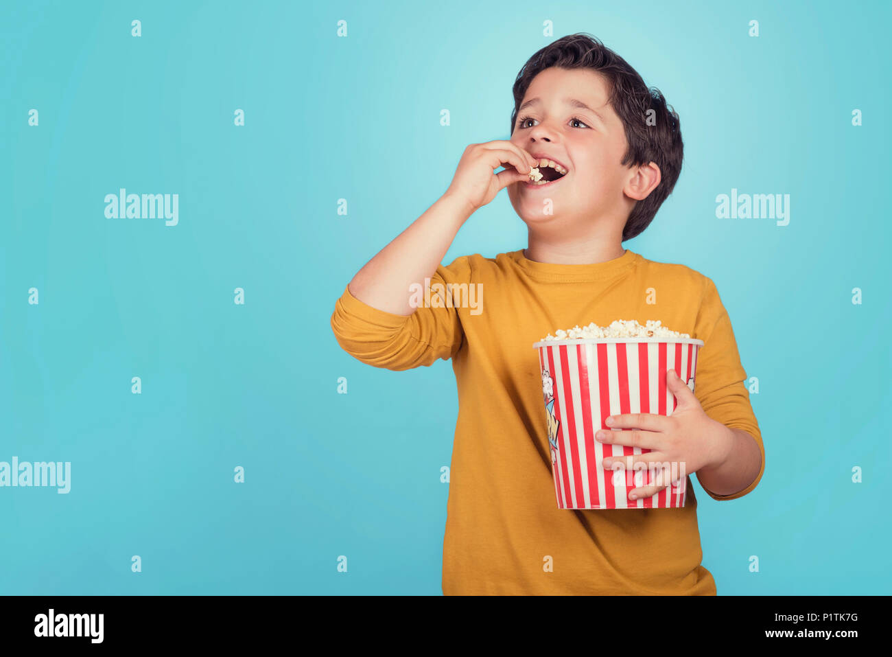 happy boy with popcorn on blue background Stock Photo - Alamy
