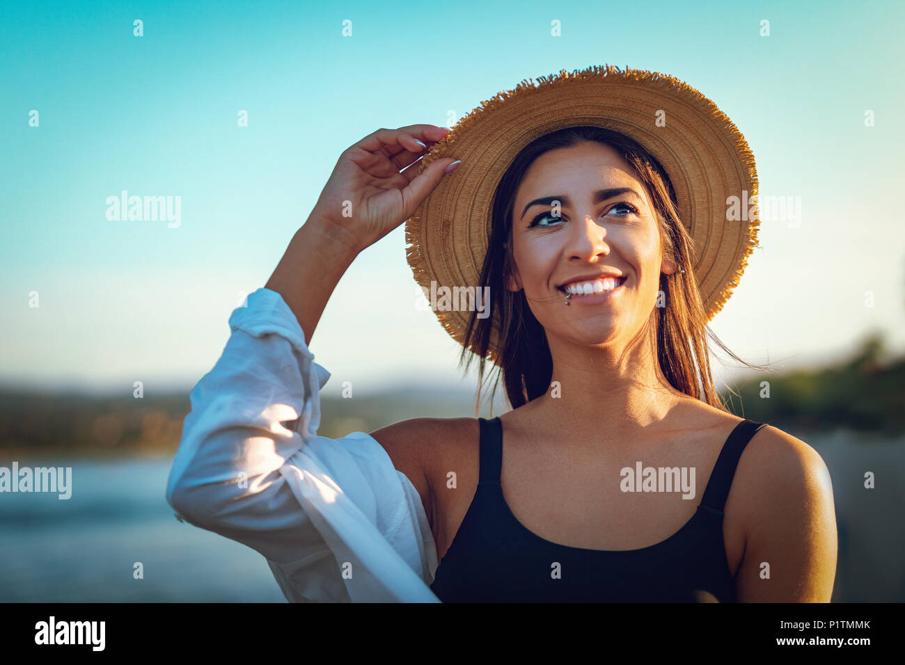 Portrait of a young woman in straw hat relaxing at sunset time on the ...
