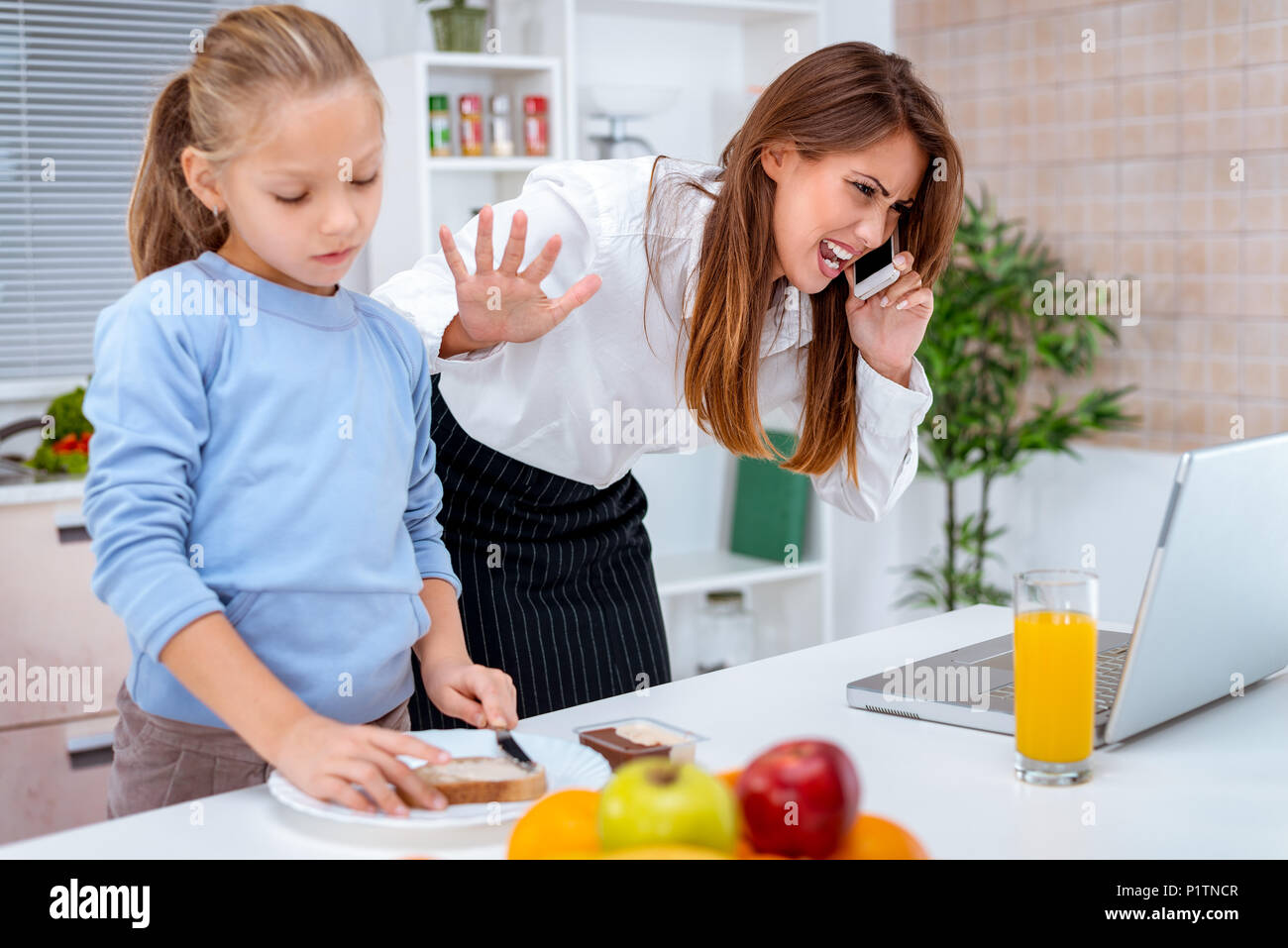 A little girl prepares a breakfast while her overworked mother phoning ...