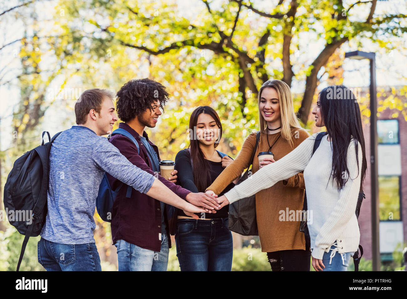 Five ethnically diverse student friends standing in a university campus ...