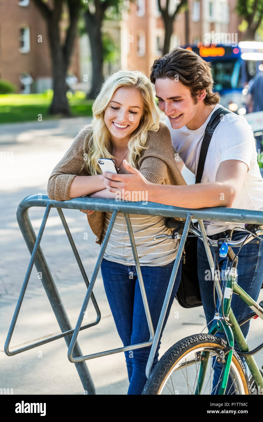 A young couple stands together at a bike rack on the university campus ...