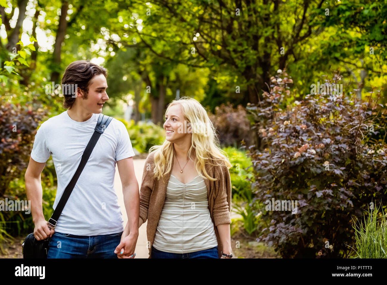 A young couple walking down a path on the university campus holding ...