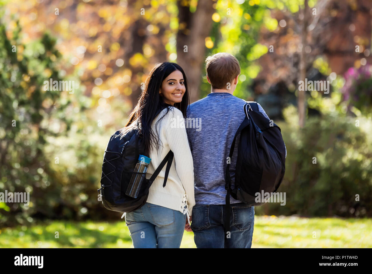 University student couple walking on a path holding hands, the young ...