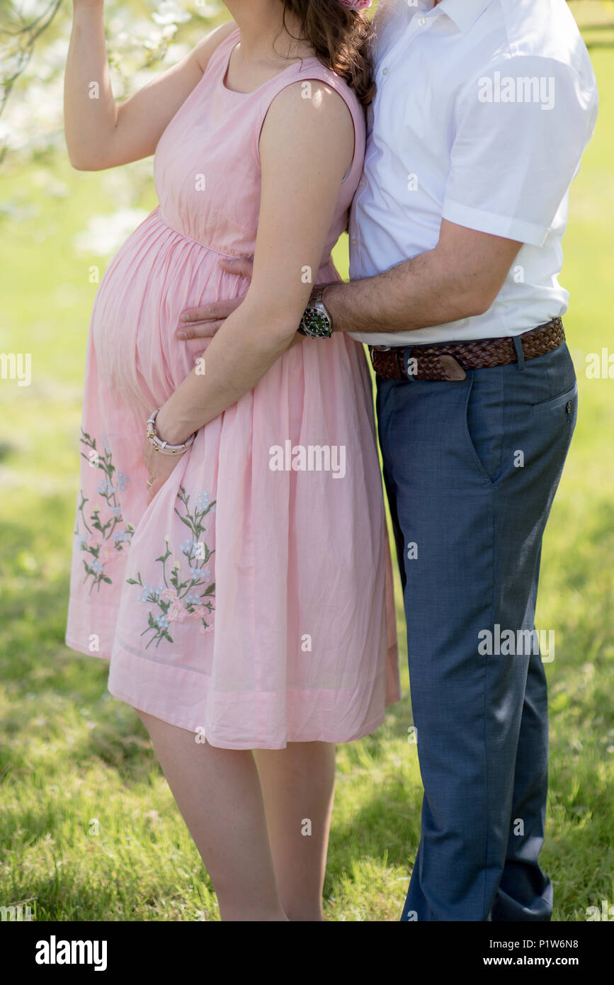 Happy and young pregnant couple hugging in nature - Detail of young ...