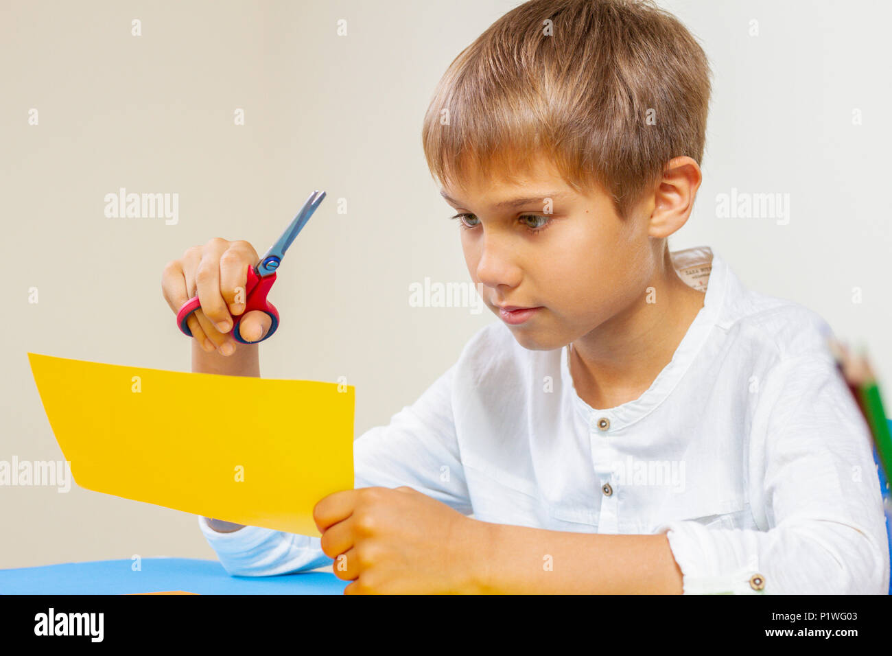 Child cutting colored paper with scissors at the table Stock Photo - Alamy