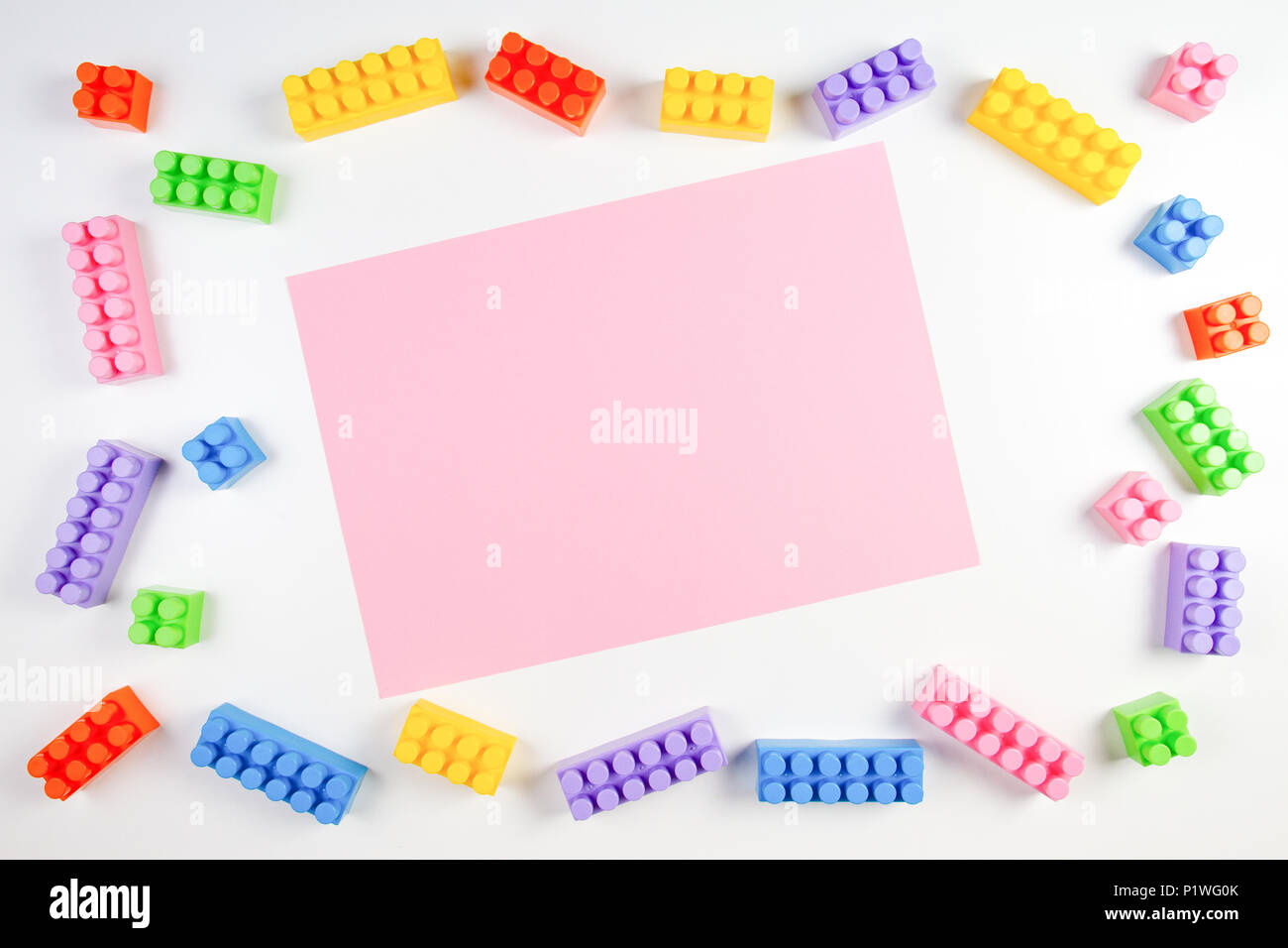 Colorful plastic construction blocks frame with pink blank card on ...
