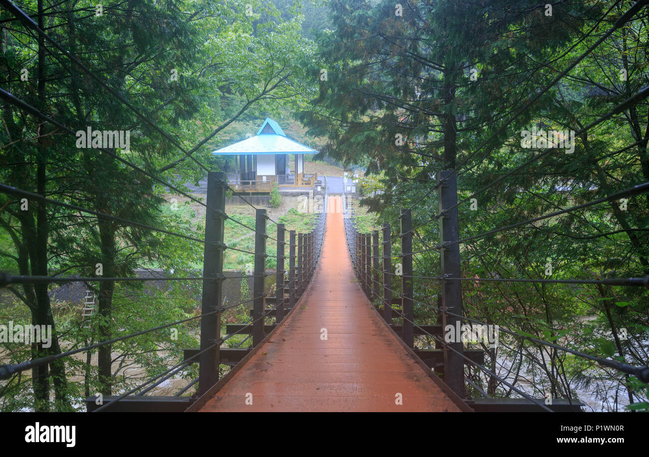 Small rest hut across narrow footbridge surrounded by green trees Stock ...