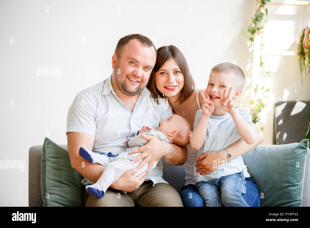 Image of smiling parents with two young sons sitting on sofa Stock ...