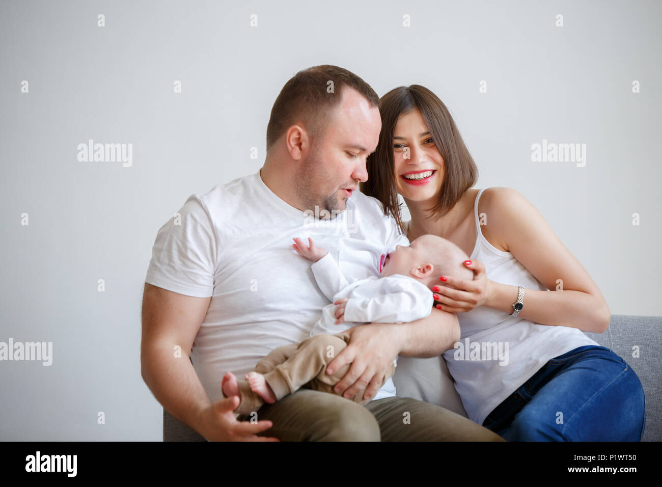 Photo of young married couple with newborn baby sitting on sofa Stock ...