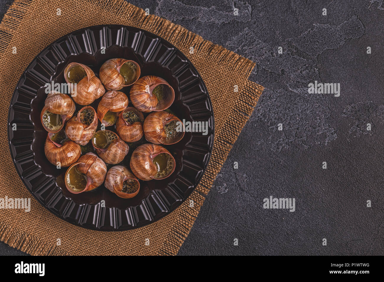 Fried snails with lemon, baguette and parsley, top view Stock Photo - Alamy