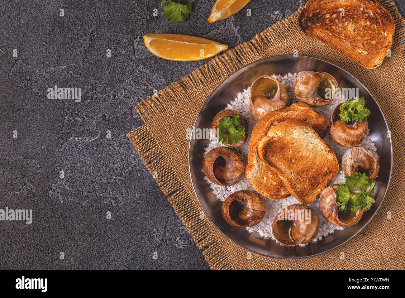 Fried snails with lemon, baguette and parsley, top view Stock Photo - Alamy