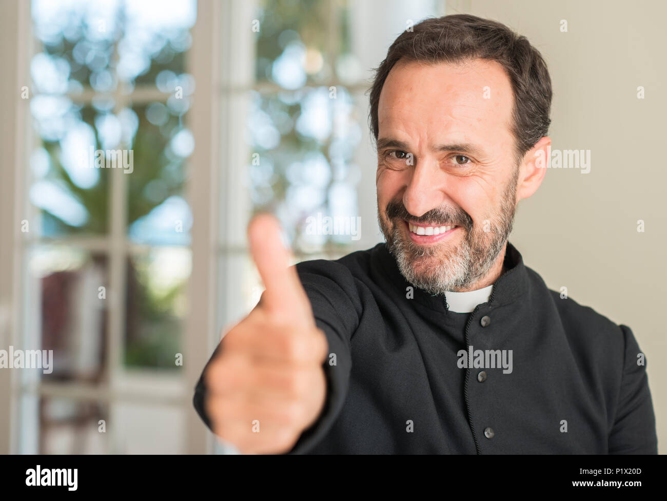 Christian priest man happy with big smile doing ok sign, thumb up with ...