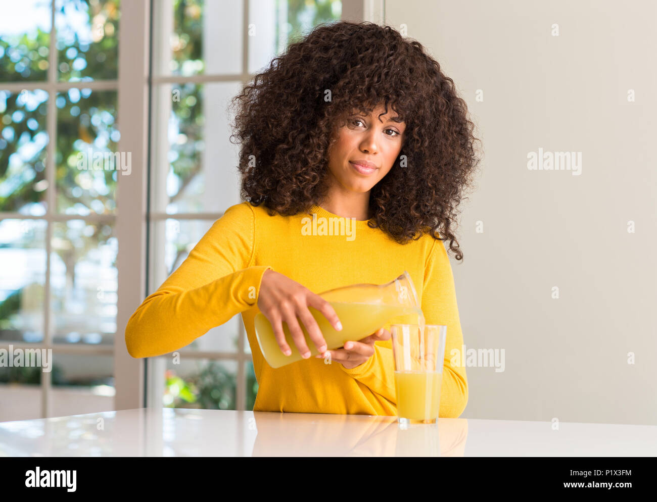 African american woman drinking healthy fruit juice at home with a ...