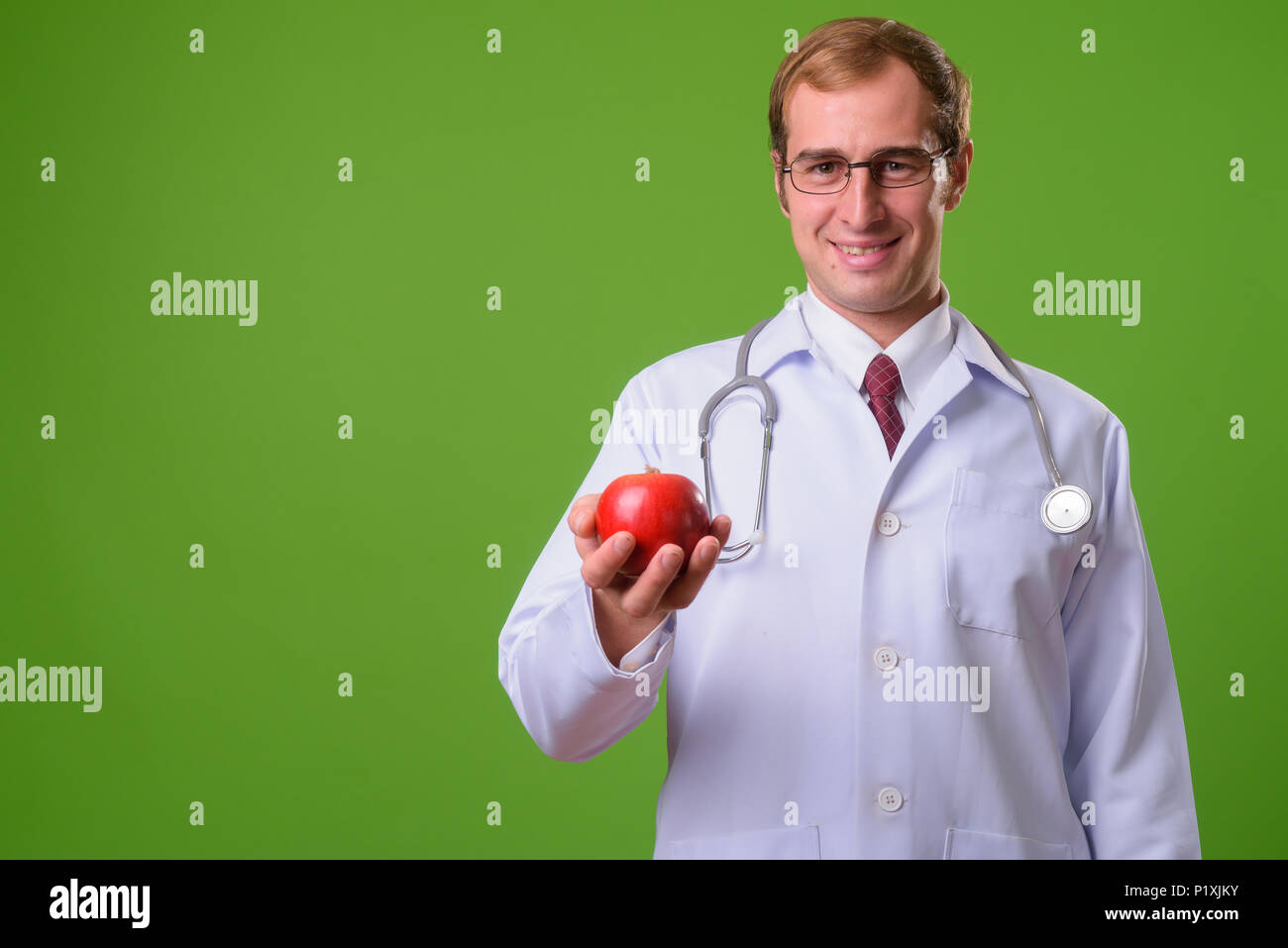 Young man doctor against green background Stock Photo - Alamy