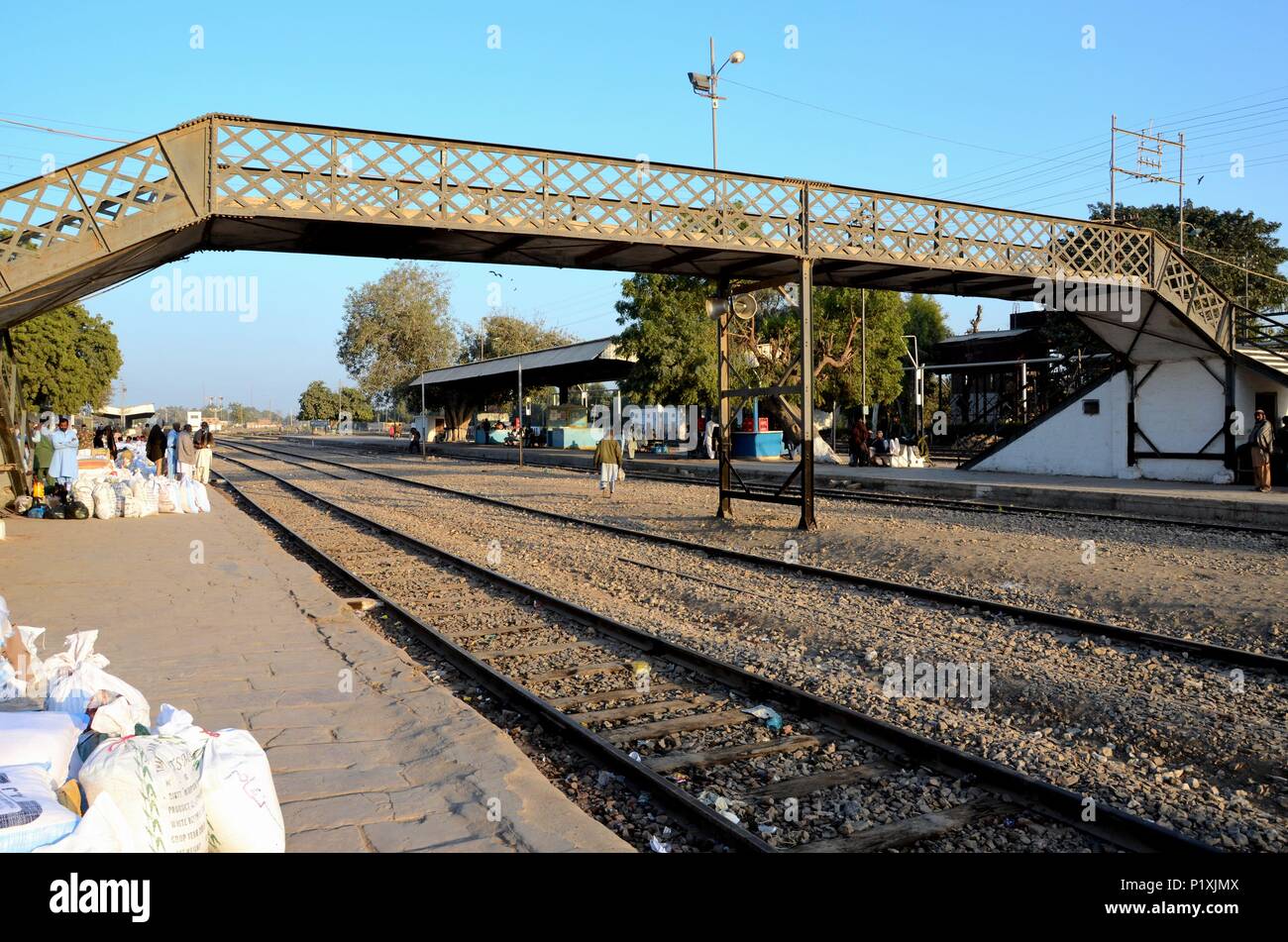 Travelers and traders wait with goods and wares at train station ...